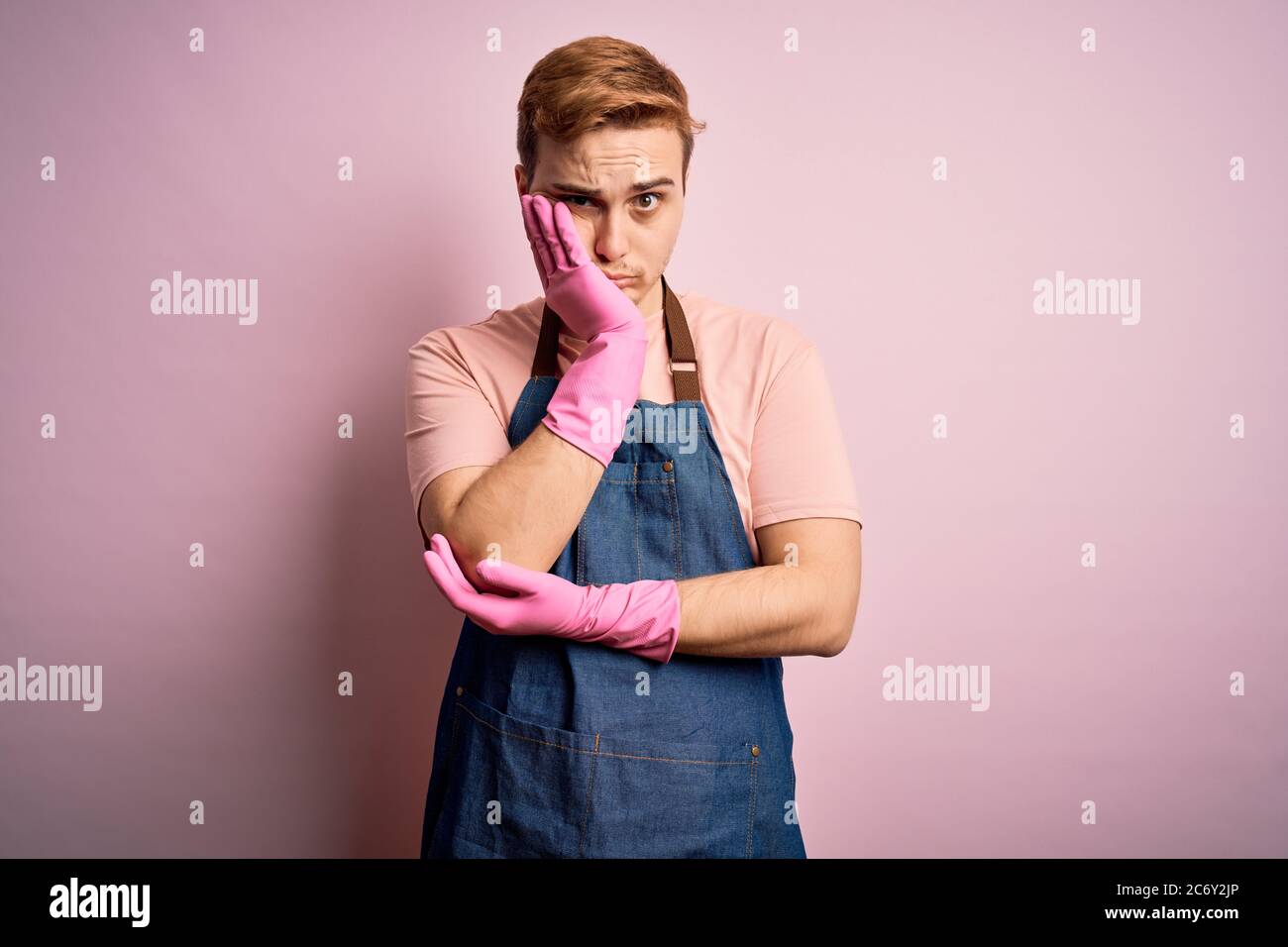 Young Handsome Redhead Cleaner Man Doing Housework Wearing Apron And Gloves Thinking Looking