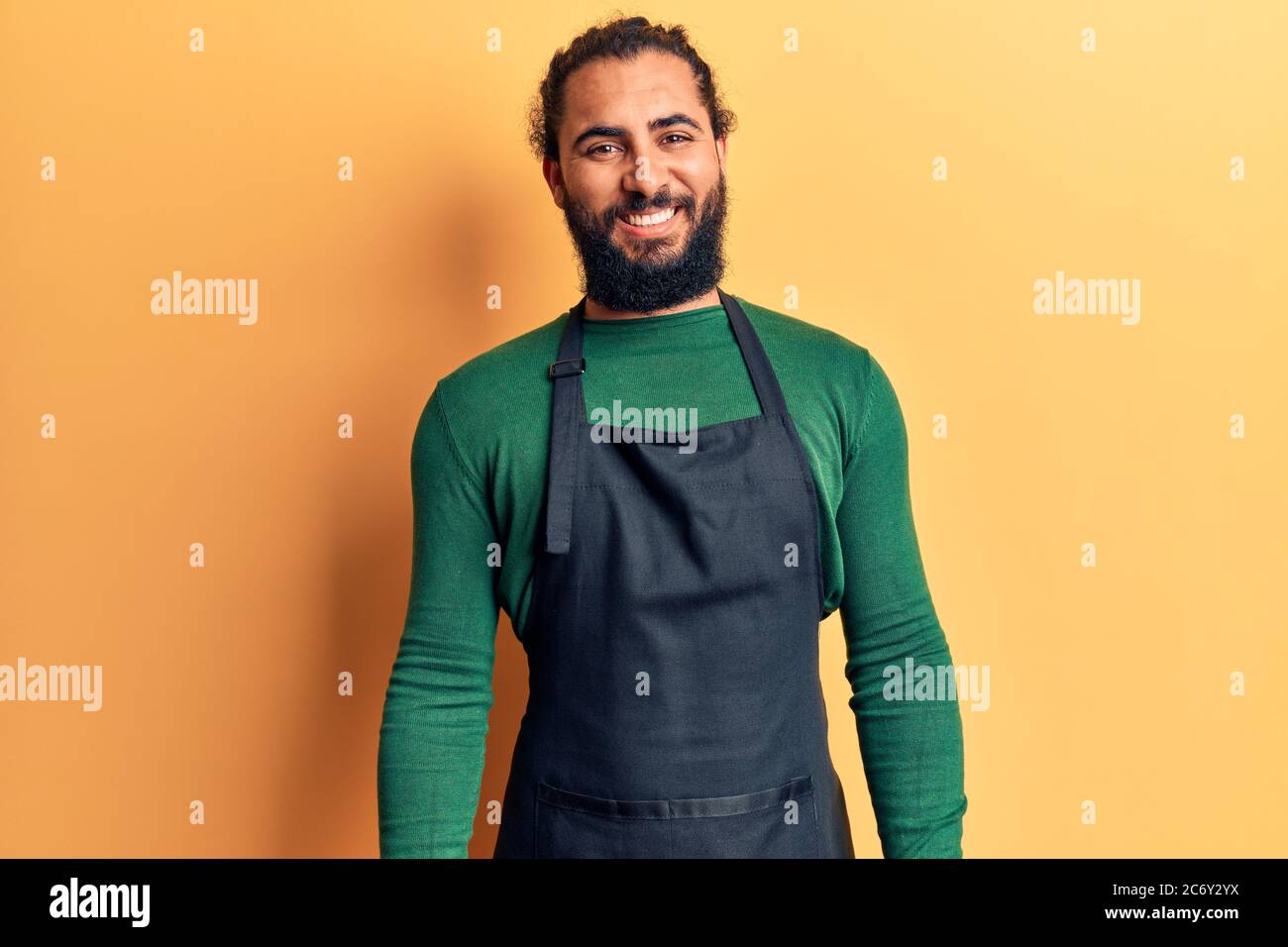 Young arab man wearing barber apron looking positive and happy standing ...