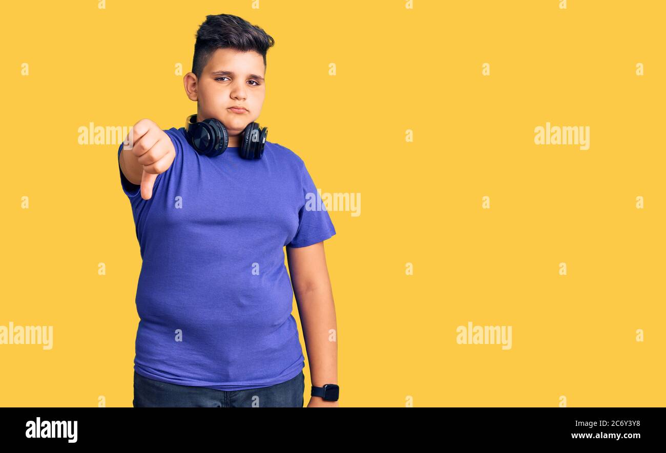 Little boy kid listening to music wearing headphones looking unhappy ...