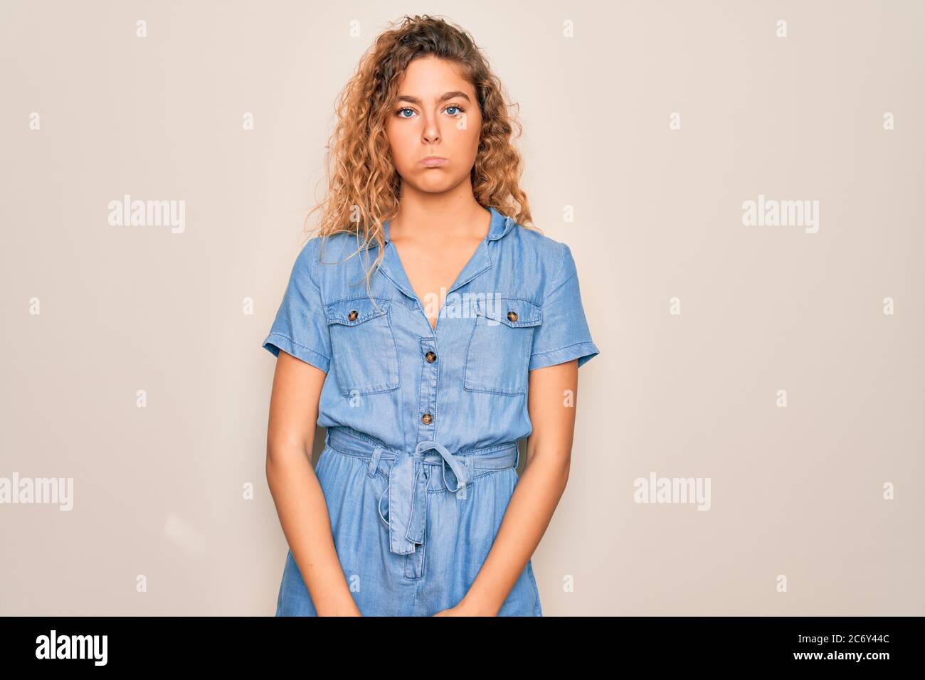 Young beautiful woman with blue eyes wearing casual denim dress over ...
