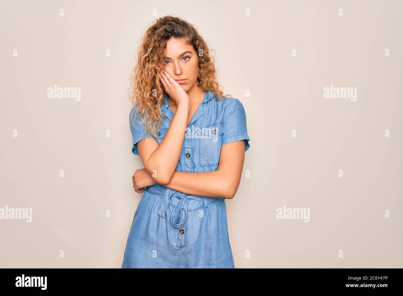 Young beautiful woman with blue eyes wearing casual denim dress over ...