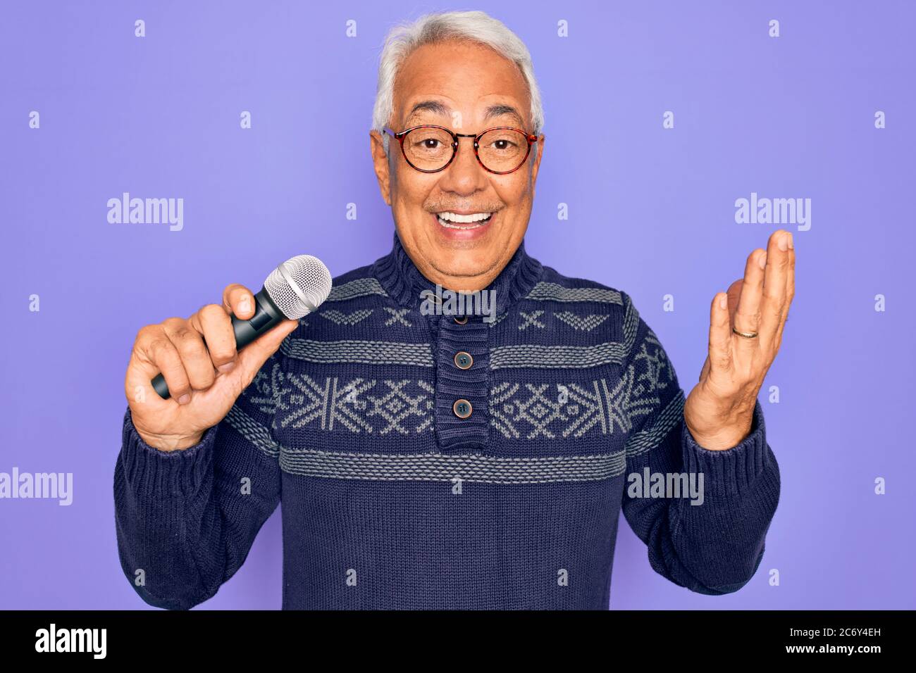 Middle age senior grey-haired singer man singing using music microphone ...