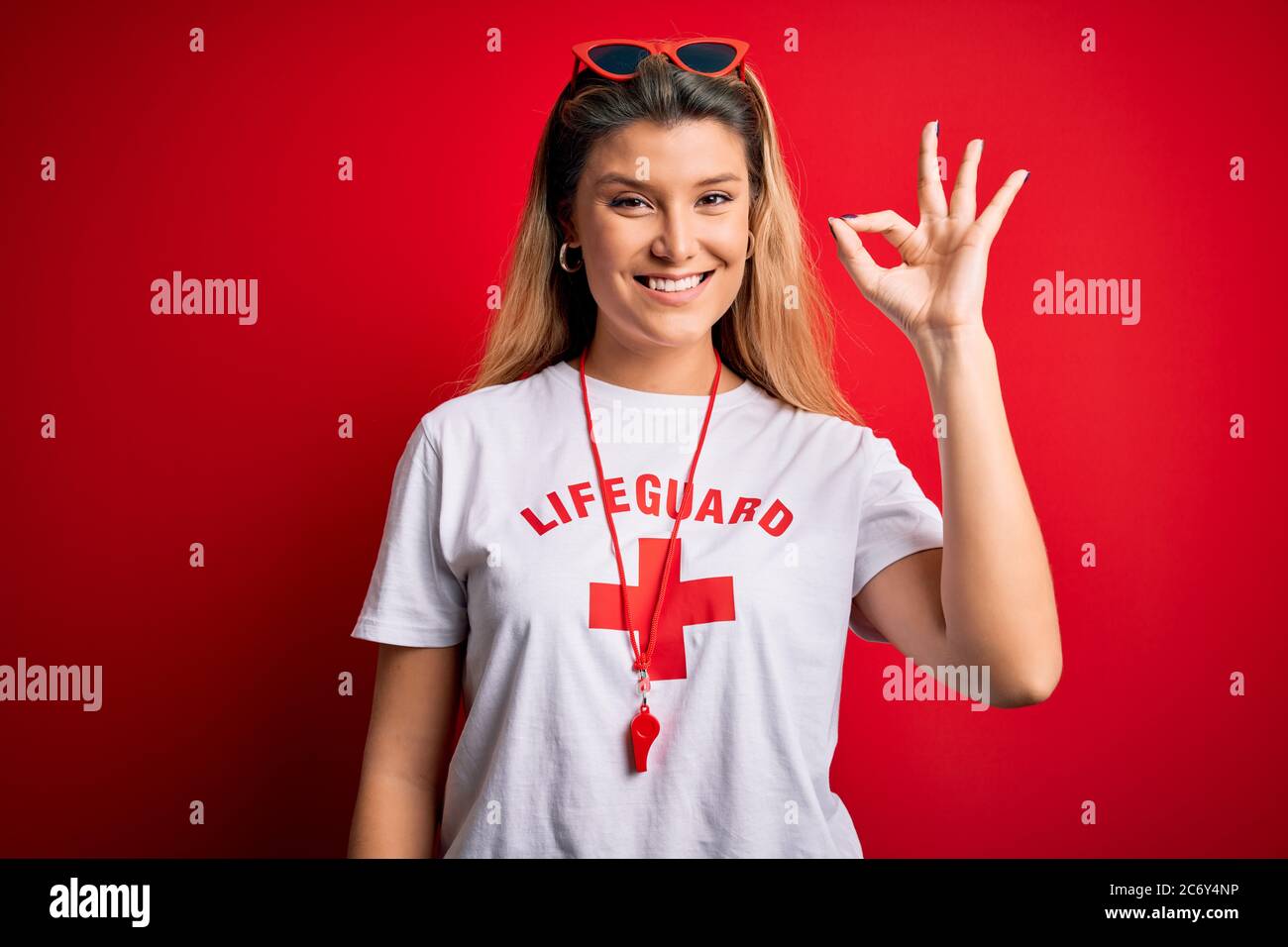Young beautiful blonde lifeguard woman wearing t-shirt with red cross ...