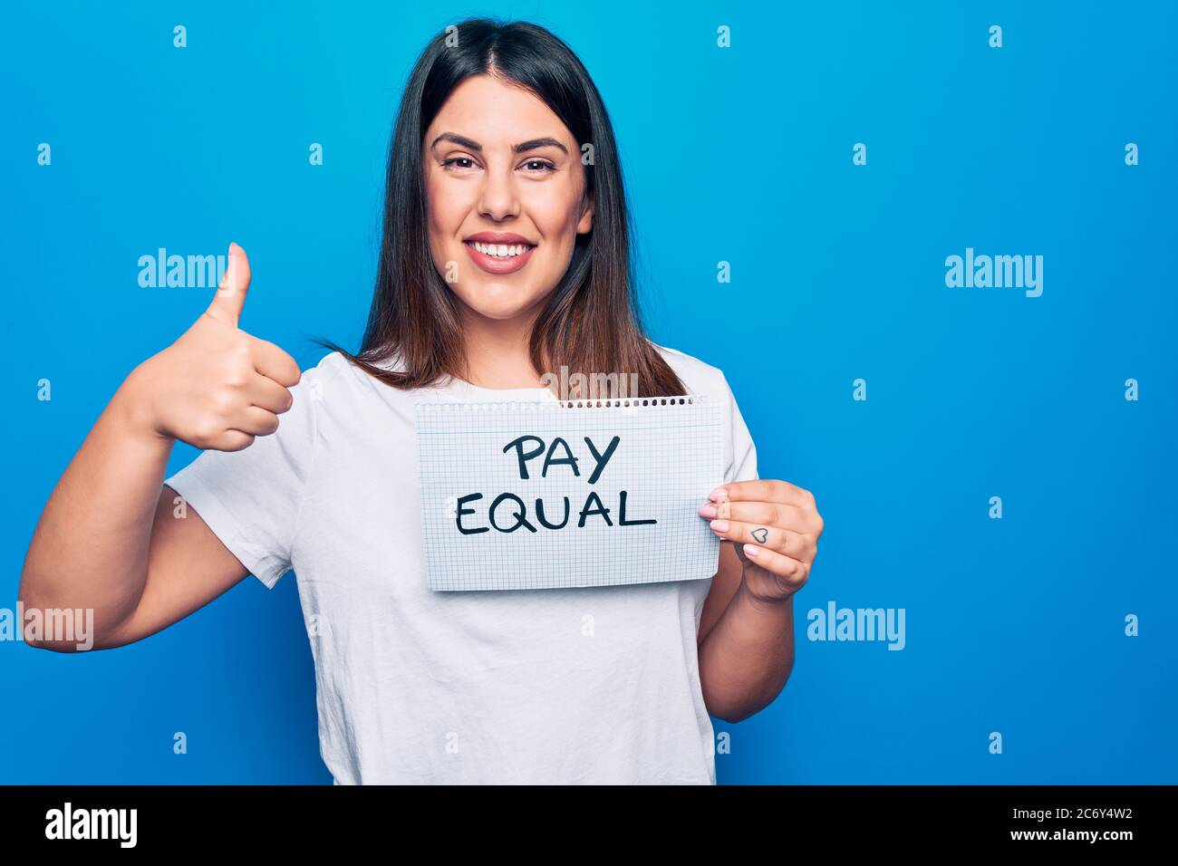 Young beautiful woman asking for gender equality holding paper with pay ...