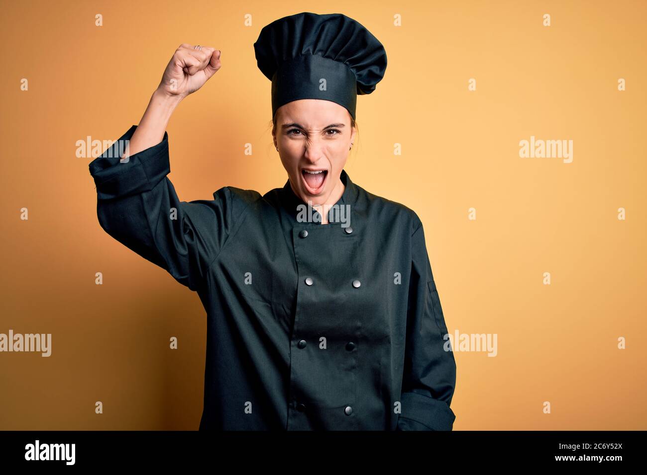 Young beautiful chef woman wearing cooker uniform and hat standing over ...
