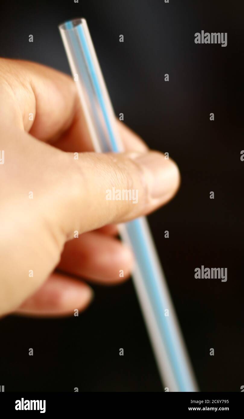 Someone holds a plastic straw Stock Photo - Alamy
