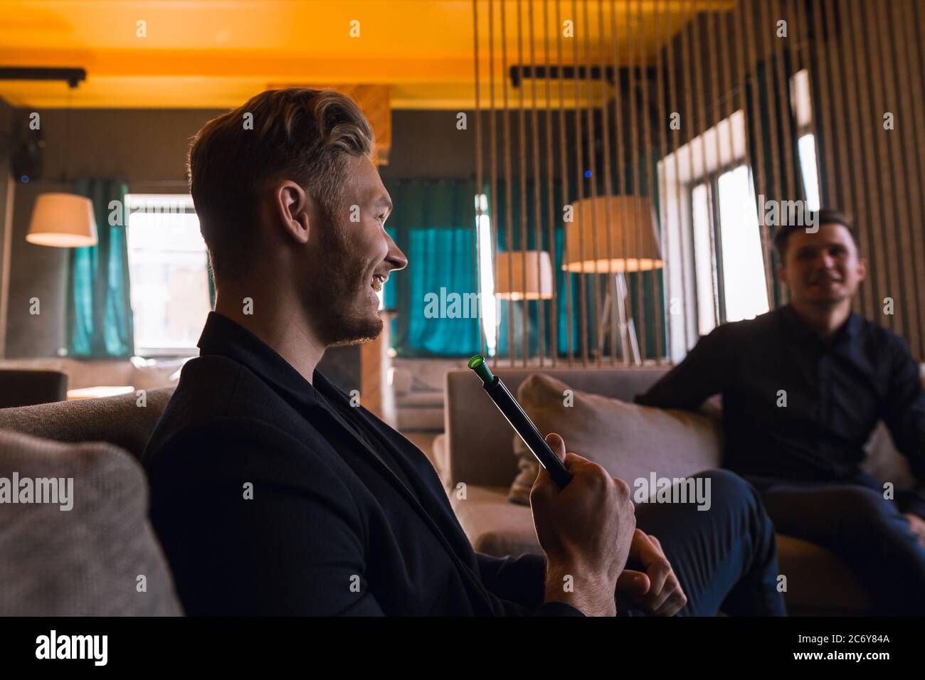 Men relax and smoke hookah in a stylish loft cafe with a modern design ...