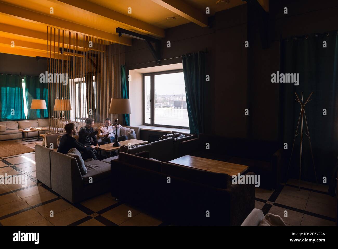 Men relax and smoke hookah in a stylish loft cafe with a modern design ...