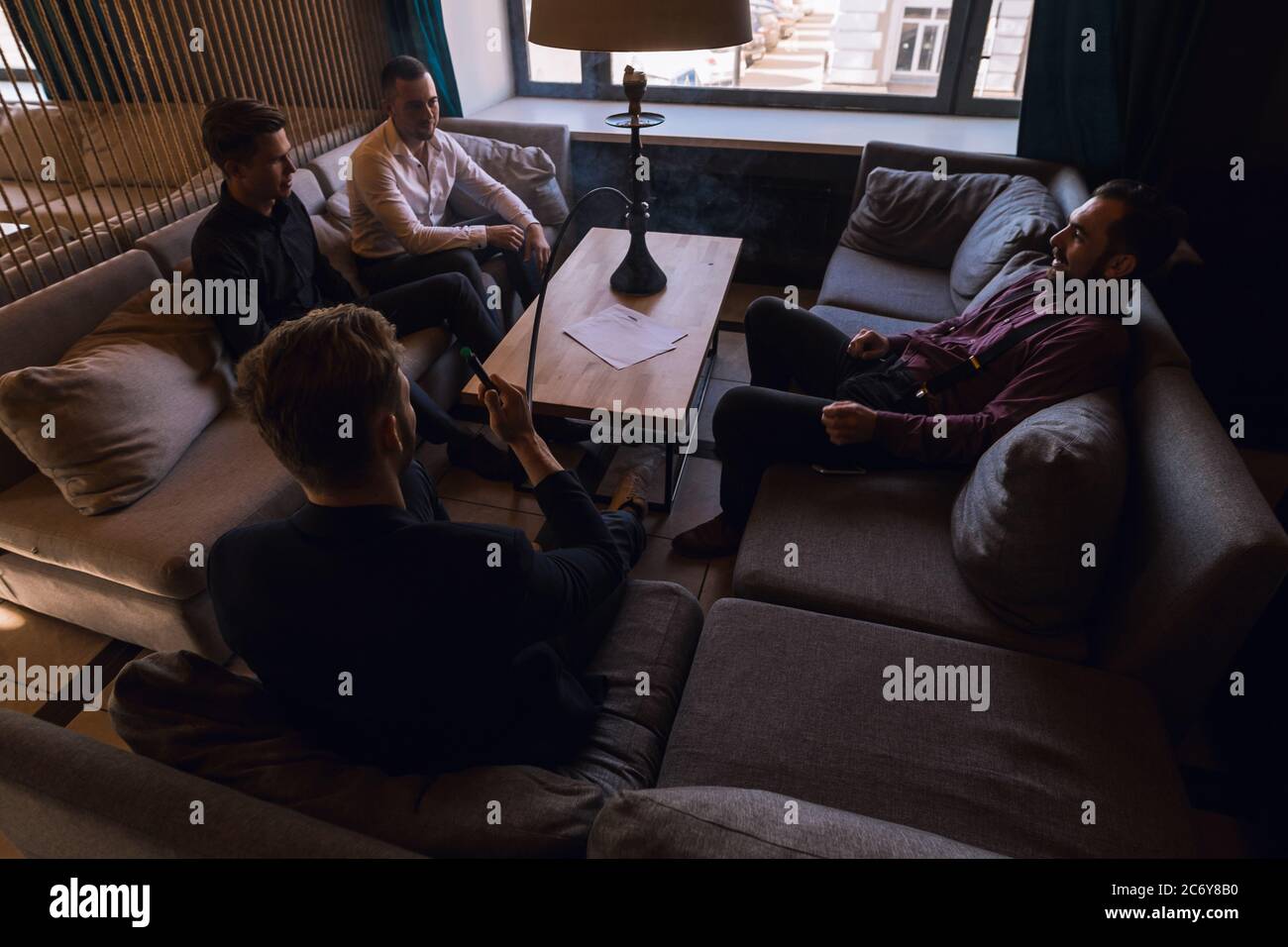 Men relax and smoke hookah in a stylish loft cafe with a modern design ...