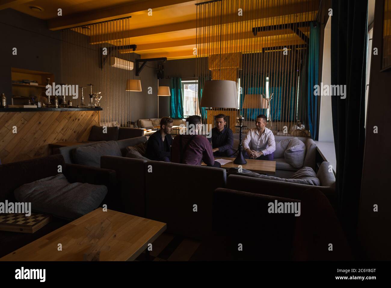 Men relax and smoke hookah in a stylish loft cafe with a modern design ...