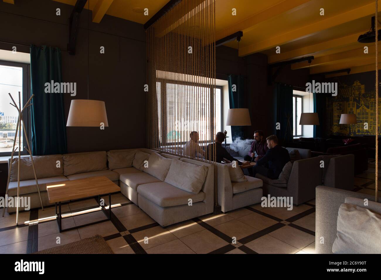 Men relax and smoke hookah in a stylish loft cafe with a modern design ...