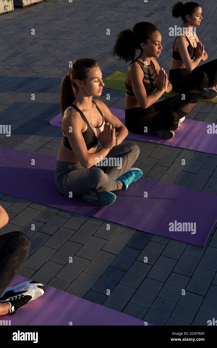 Multicultural young women meditate doing yoga on sunrise outdoor ...