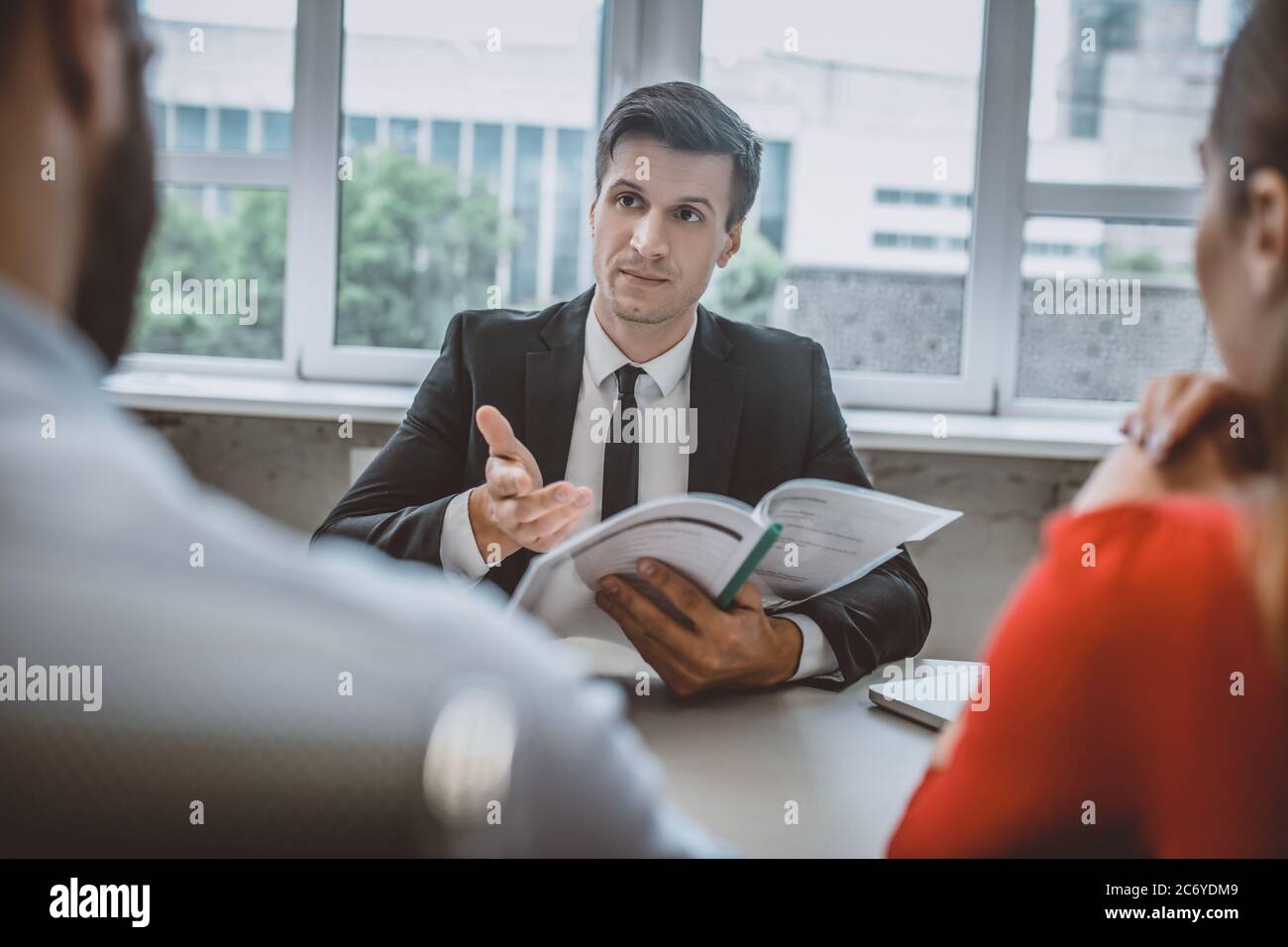Officially dressed man reading a paper to his client Stock Photo - Alamy