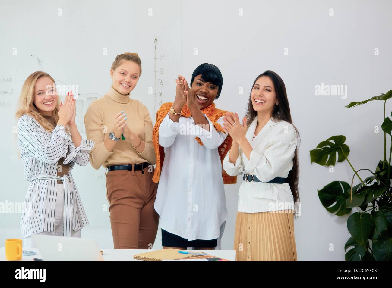 Happy positive ladies of caucasian and african appearance clapping ...