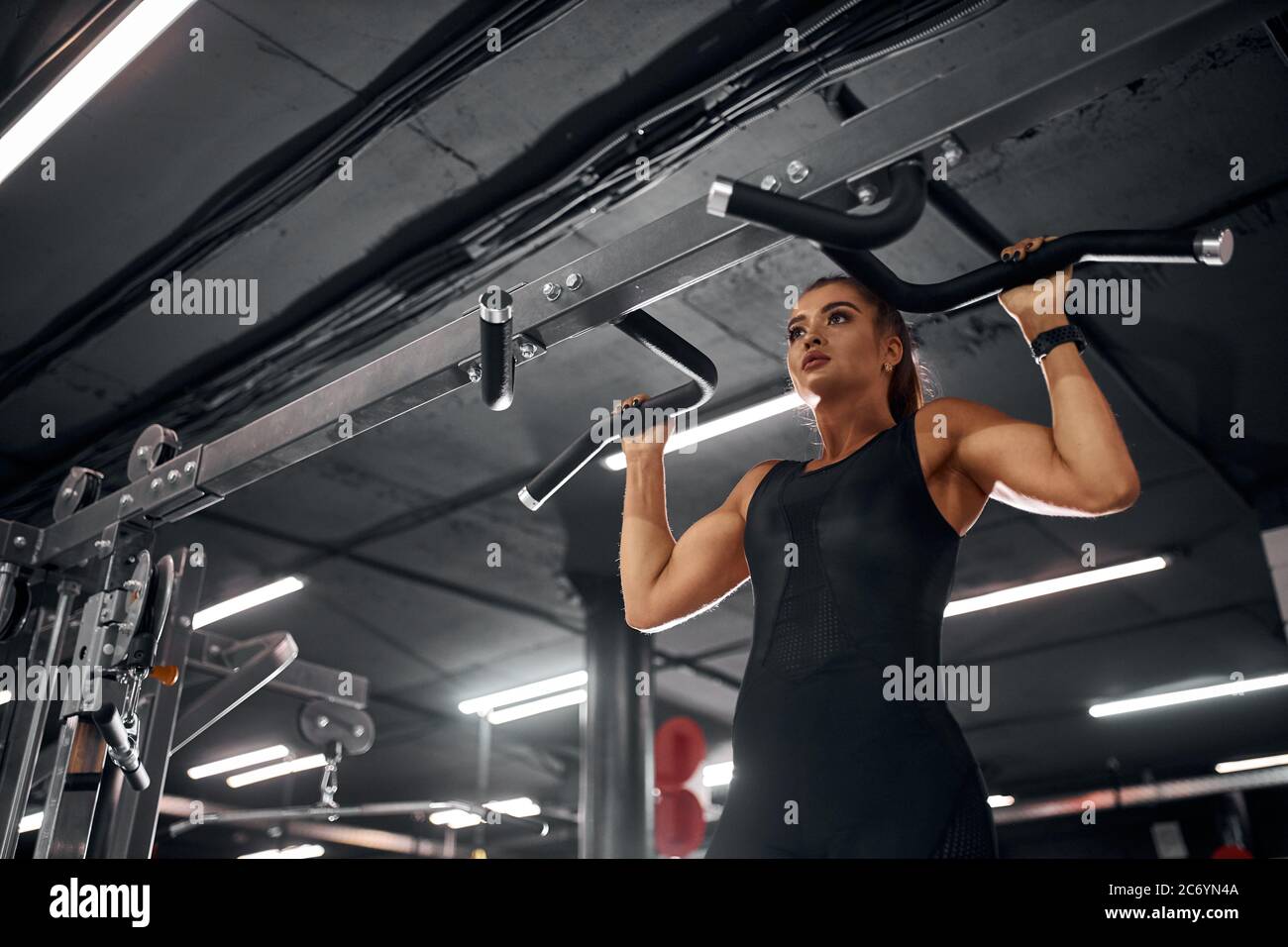 Pretty cute female bodybuilder practising with fitness machine, pumping ...