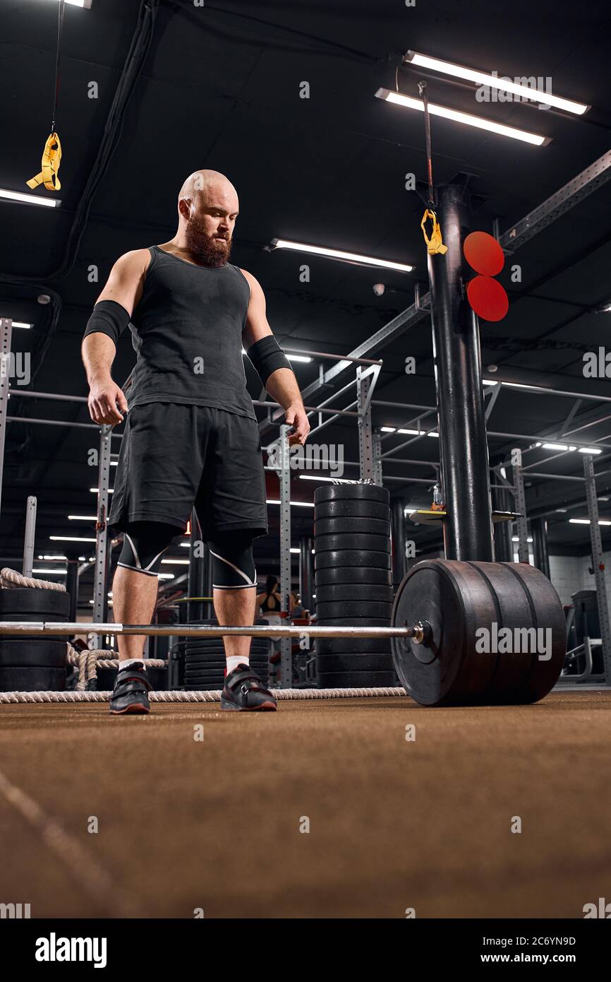 Strong brutal bodybuilder dressed in black sports singlet and shorts ...