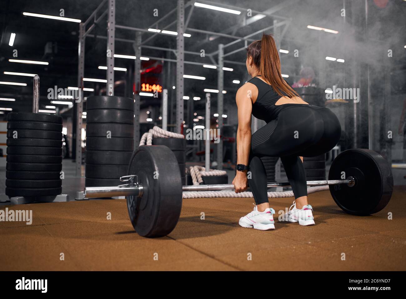 Pretty attractive female training in gym doing exercises with barbell ...
