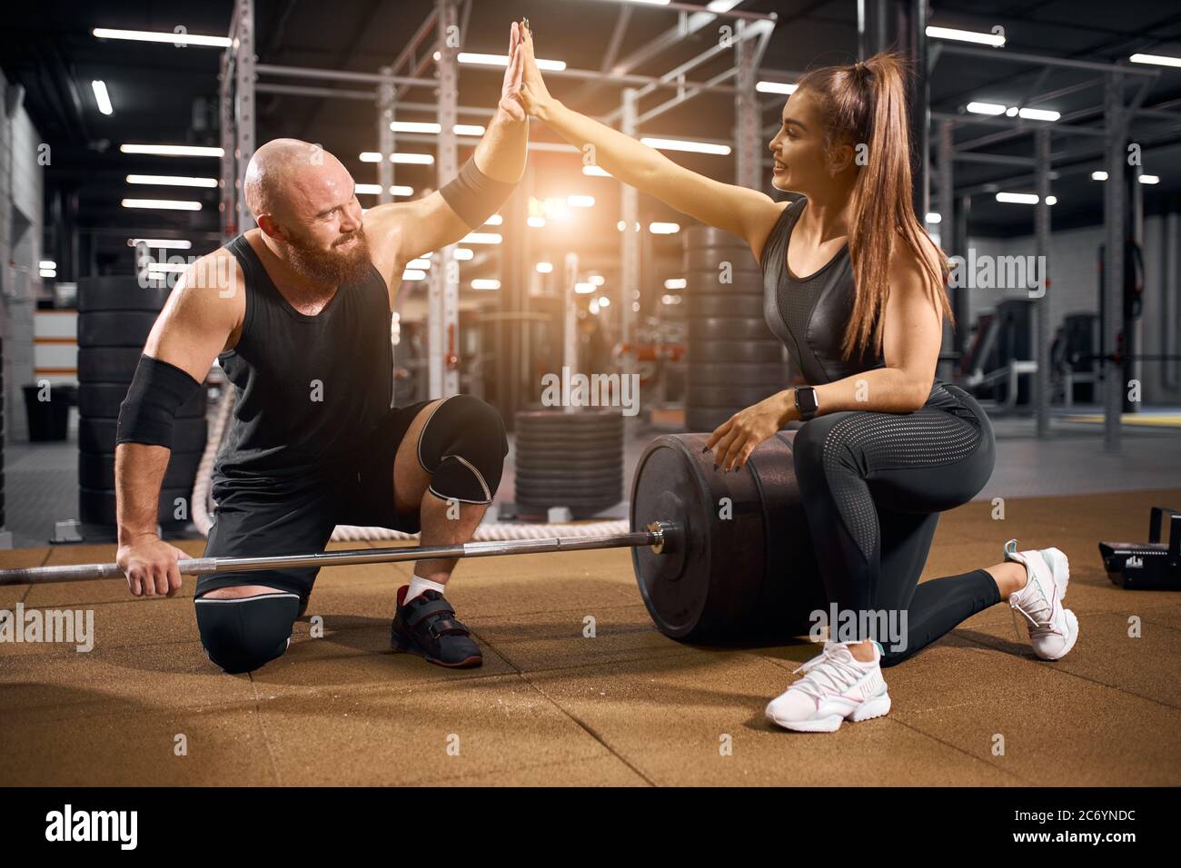 Active young couple making bet in brightly lighted gym hall, raising ...