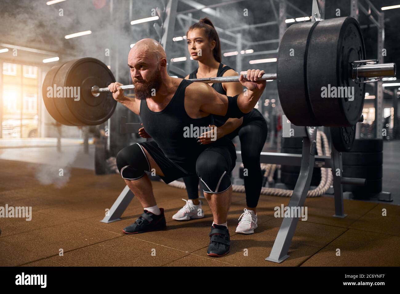 Strong brutal male powerlifter doing squats using heavy barbell, young ...
