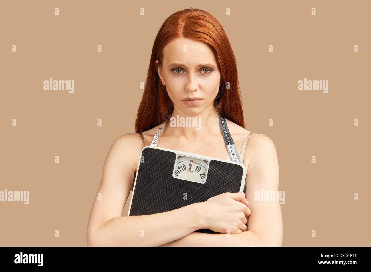 Diet and weight, young woman holding scales in hands feeling sad and ...