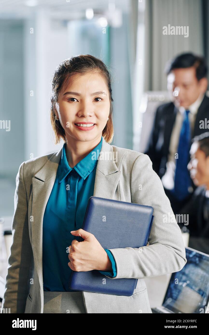 Portrait of pretty smiling young female entrepreneur posing with tablet ...