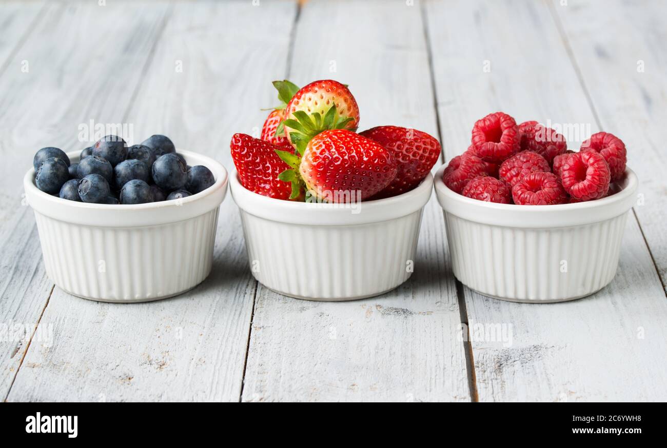 Assorted fresh juicy berries in three tiny bowls, blueberry, strawberry ...