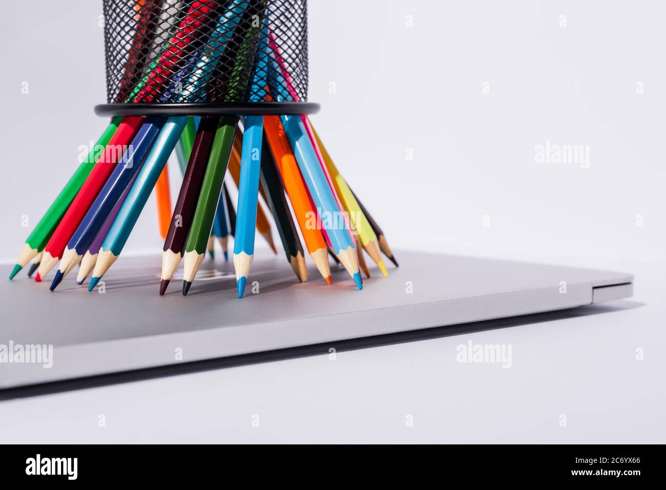colored pencils in pencil holder on modern laptop on white background ...