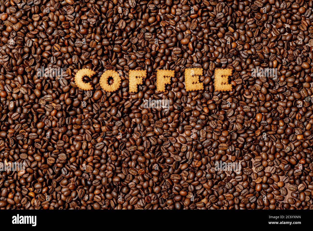 The word COFFEE made from biscuit letters on a dark coffee bean ...