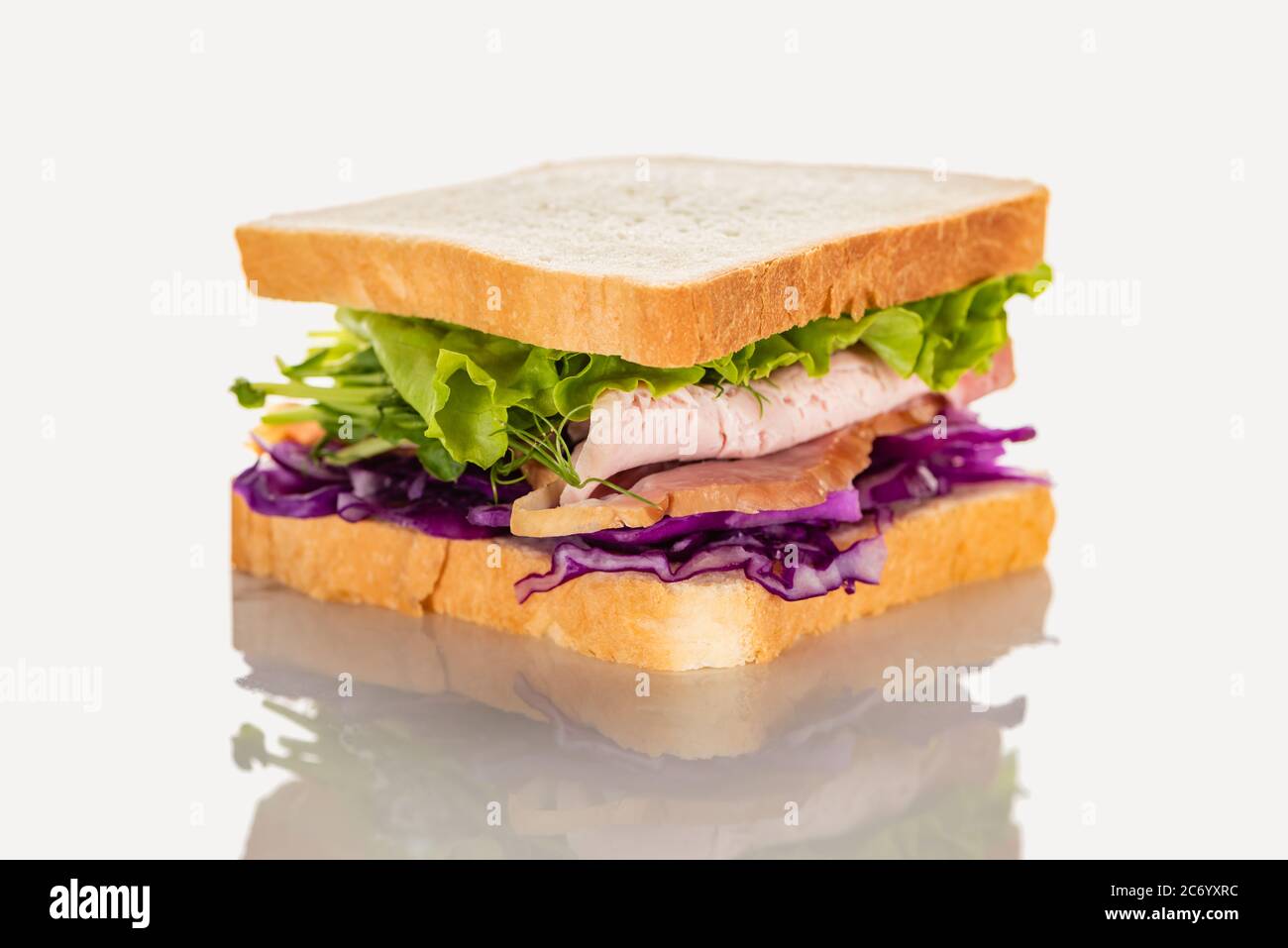fresh sandwich with red cabbage, lettuce and meat on white surface ...