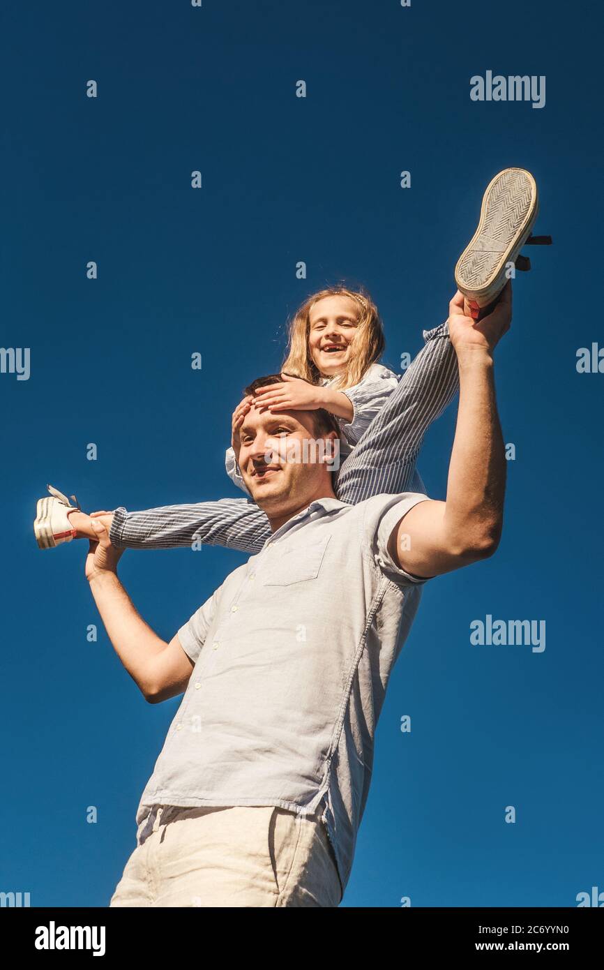 Piggyback of baby and dad. Girl do the split. Blue sky background ...
