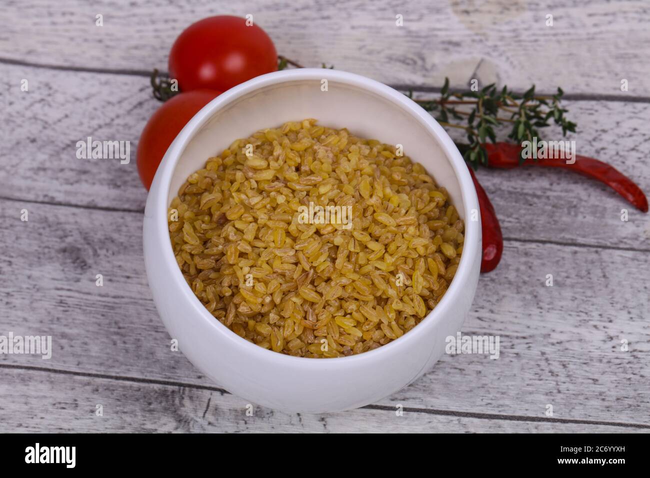 Raw golden bulgur in the bowl with tomatoes and garlic Stock Photo - Alamy