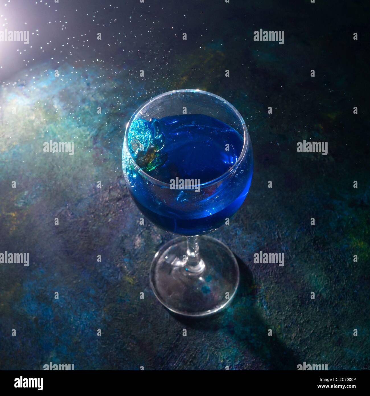 Blue cocktail in wineglass with splash on dark background with back ...