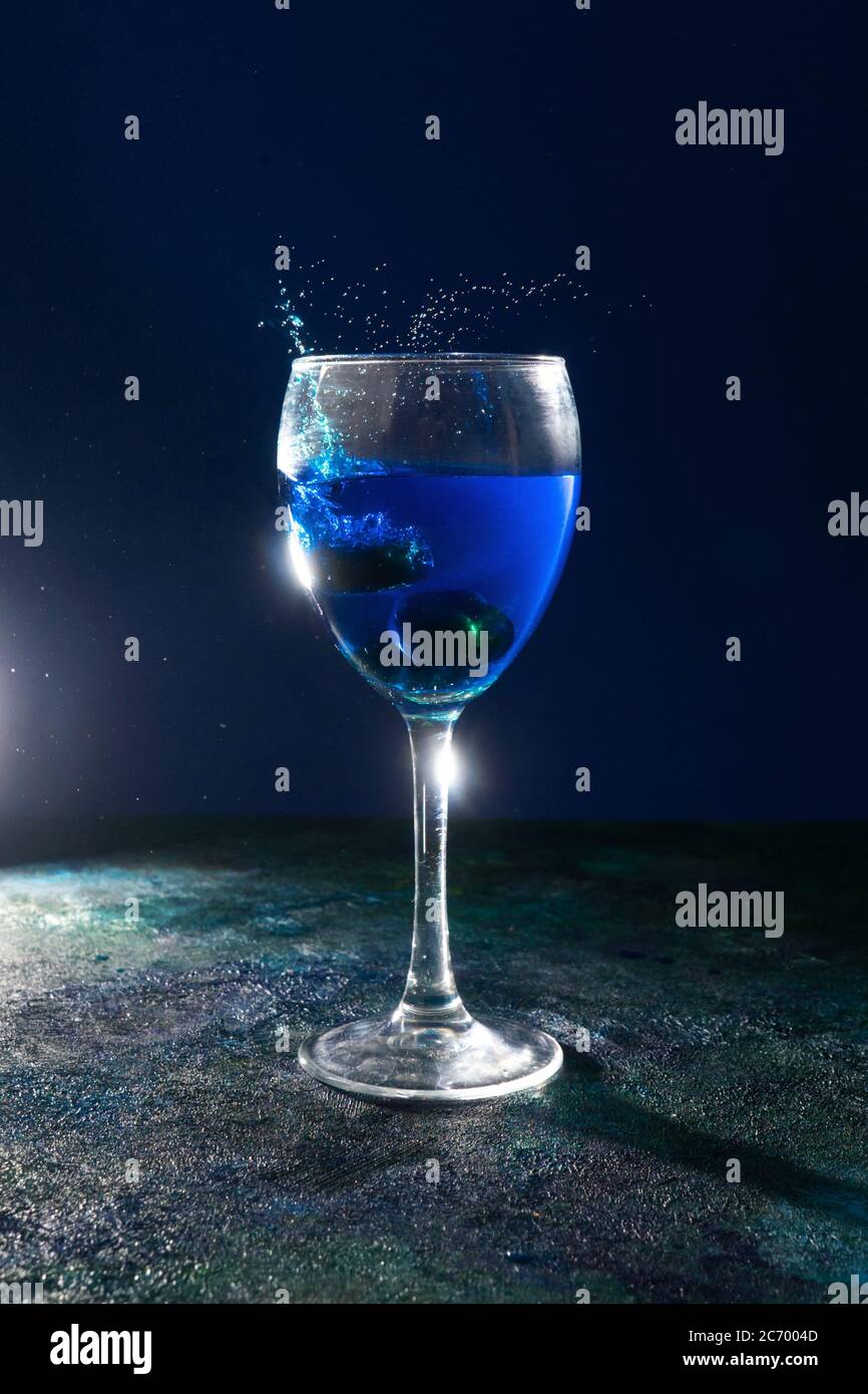 Blue cocktail in wineglass with splash on the black background Stock ...