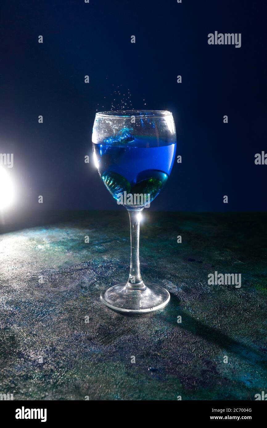 Blue cocktail in wineglass with splash on the black background Stock ...