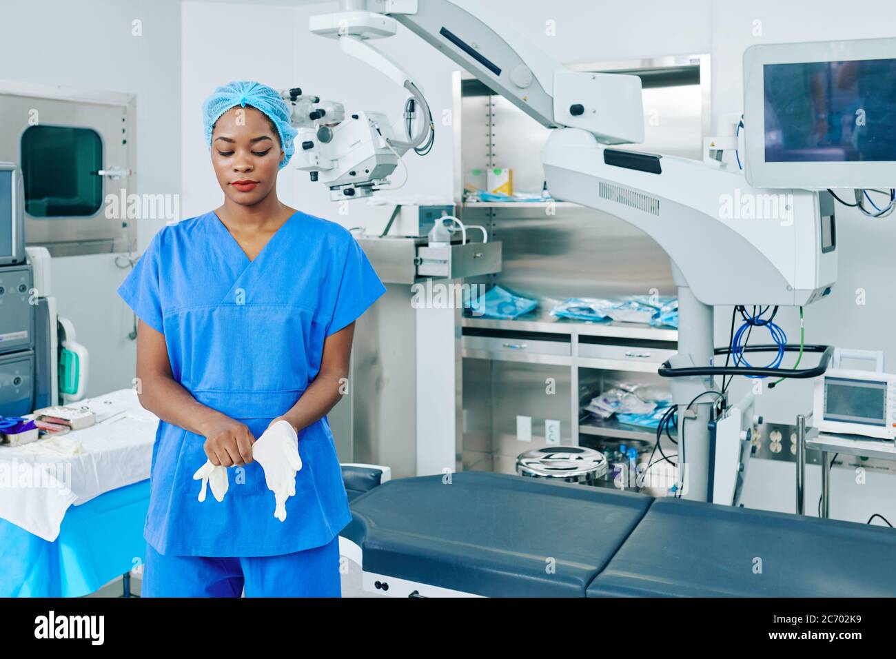 Young Black surgeon putting on rubber gloves when getting ready for ...