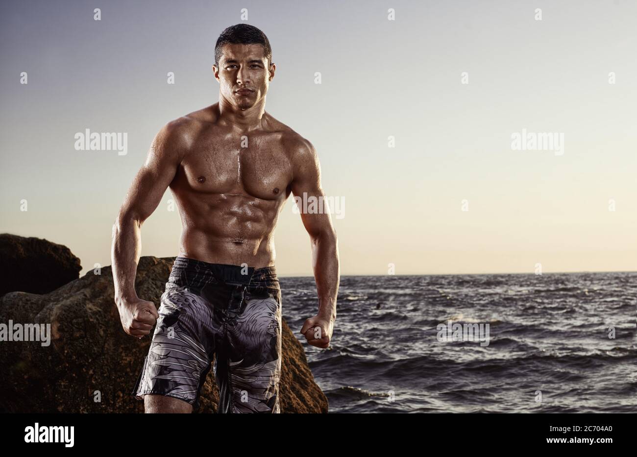 Handsome muscular young strong athlete on a beach background after ...