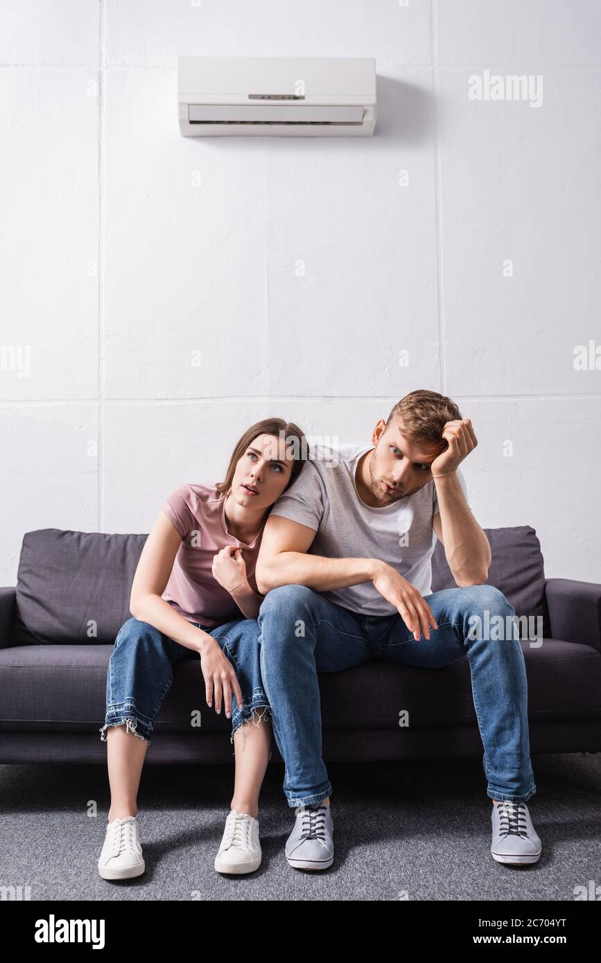 exhausted couple suffering from heat while sitting home with broken air ...