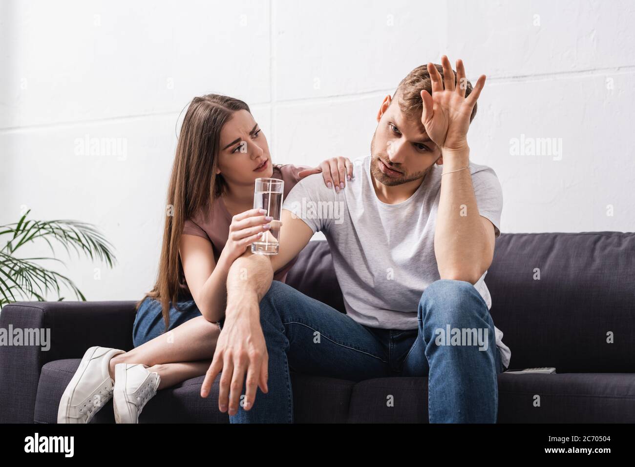 exhausted couple with glass of water at home during summer heat Stock ...