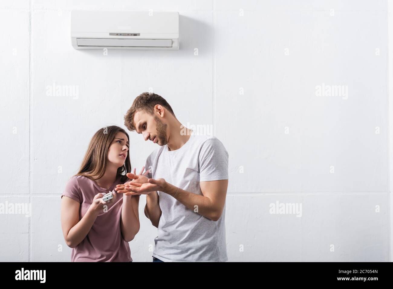 sad couple suffering from heat at home with broken air conditioner ...