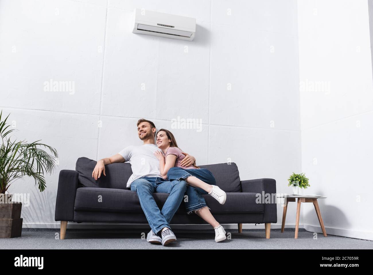 happy girlfriend and boyfriend hugging at home with air conditioner ...