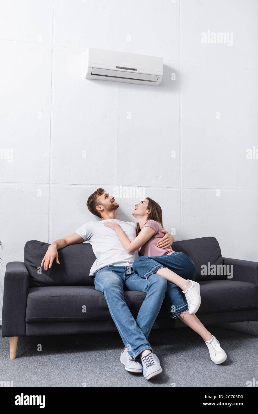 happy girlfriend and boyfriend hugging at home with air conditioner ...