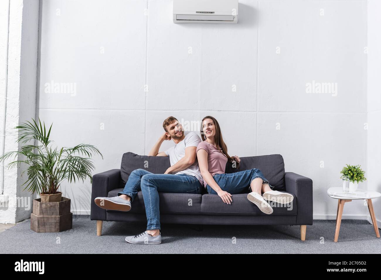 positive girlfriend and boyfriend hugging at home with air conditioner ...