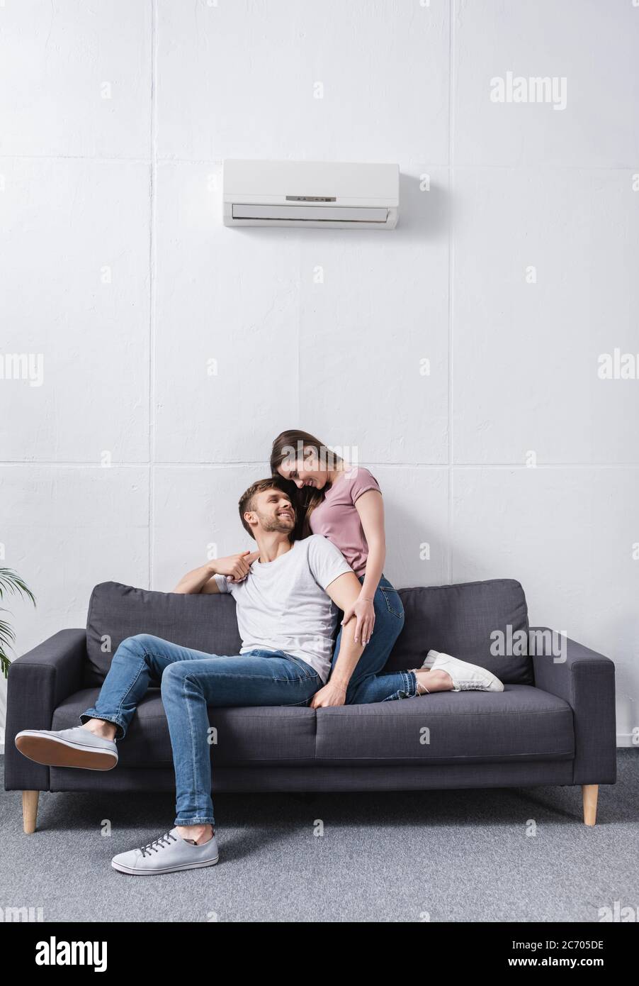 happy girlfriend and boyfriend hugging at home with air conditioner ...