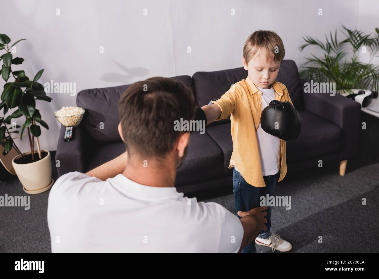 back view of man fighting with cute son in boxing gloves Stock Photo ...