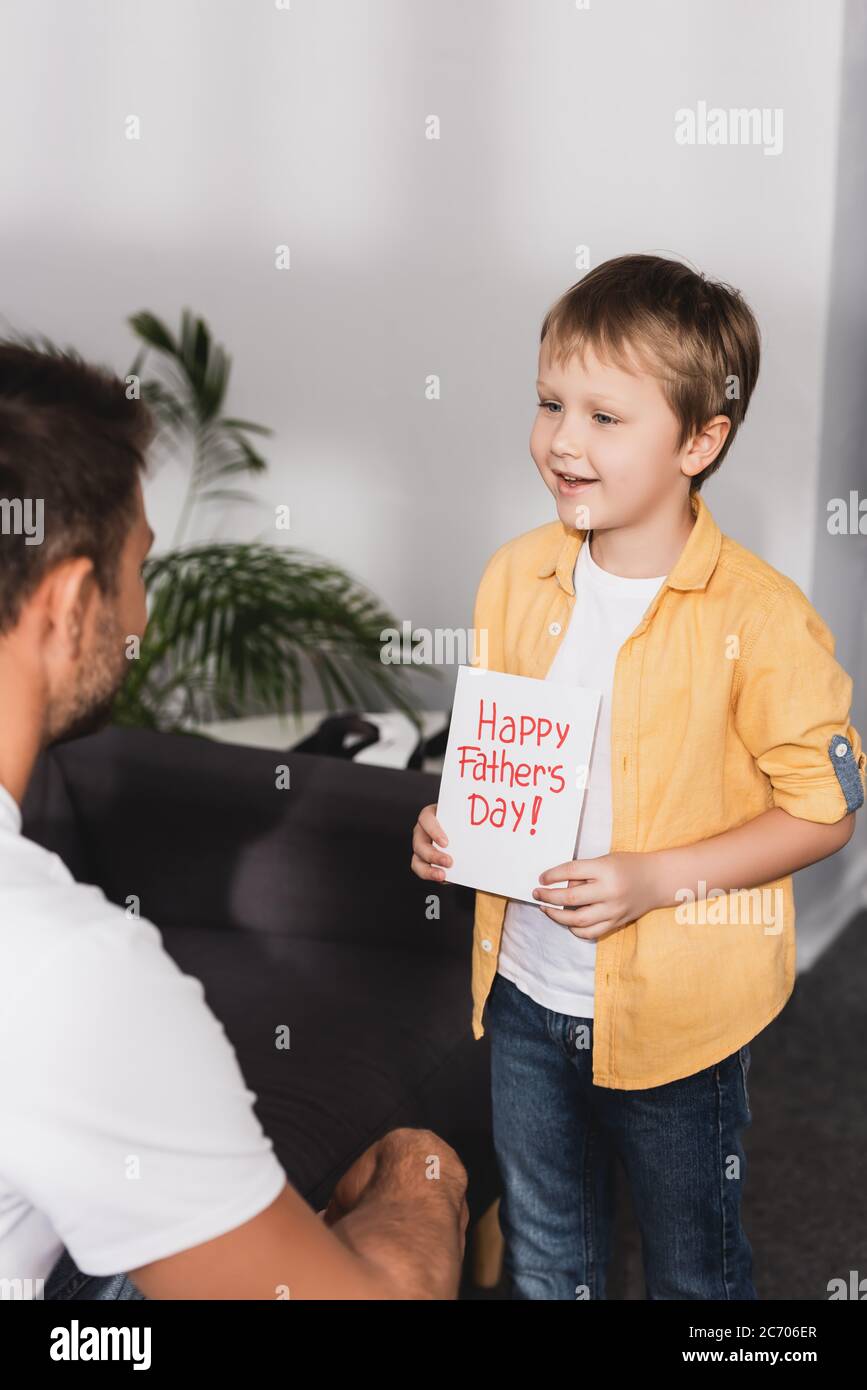 smiling boy presenting happy fathers day greeting card to father Stock ...