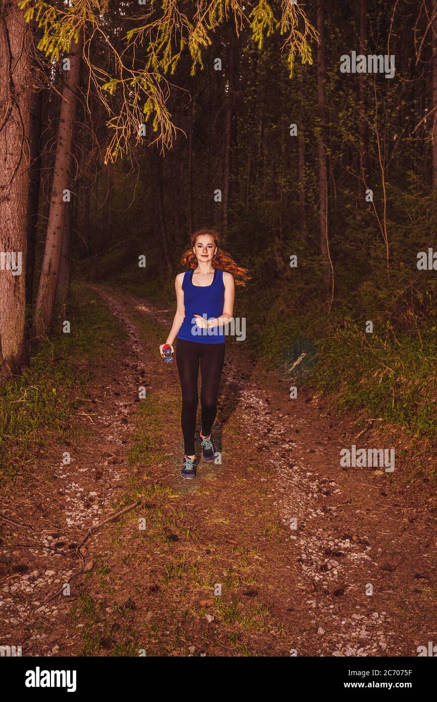 Running woman. Female runner running in dark forest Stock Photo - Alamy