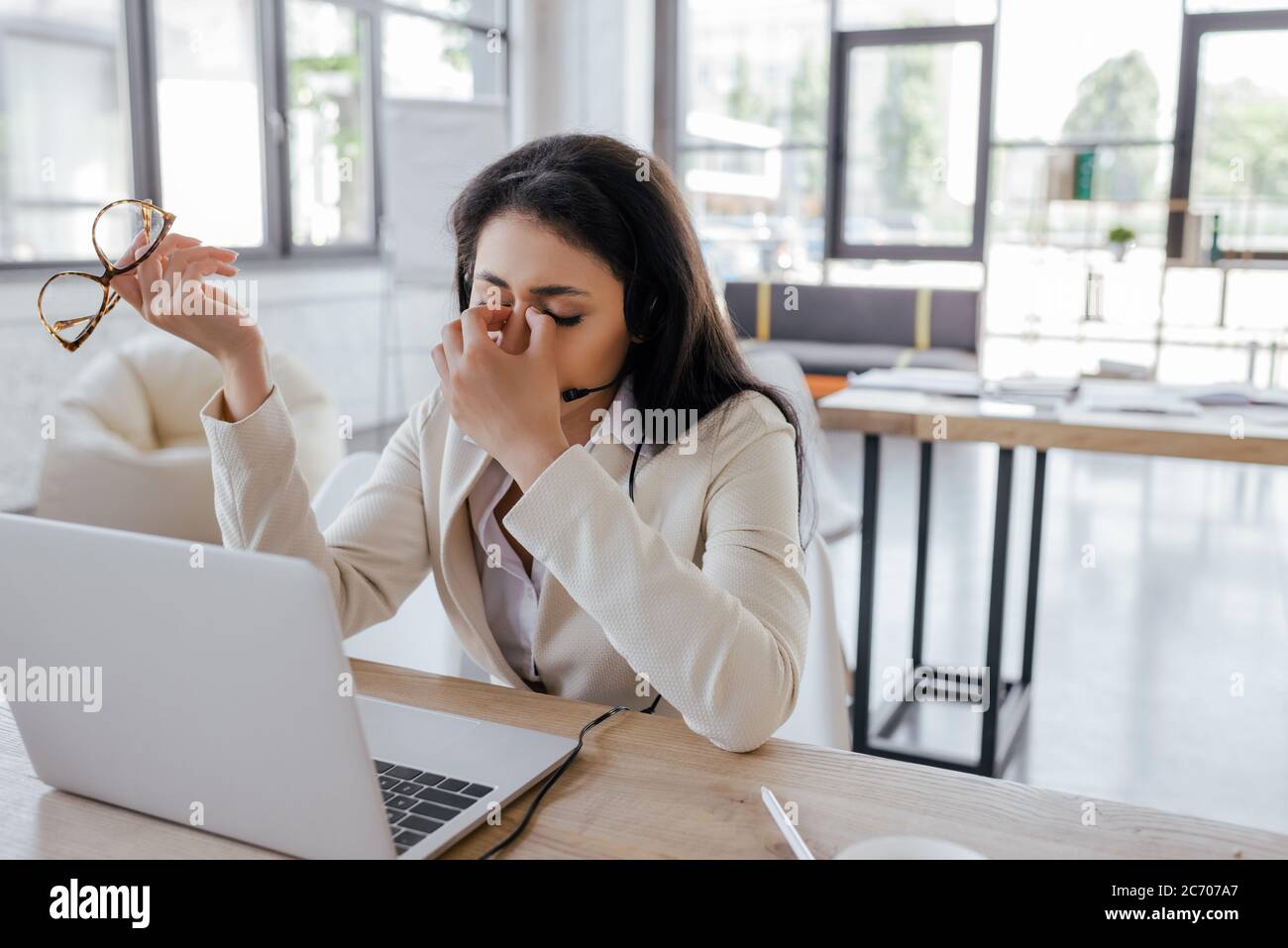 tired operator in headset touching eyes near laptop Stock Photo - Alamy