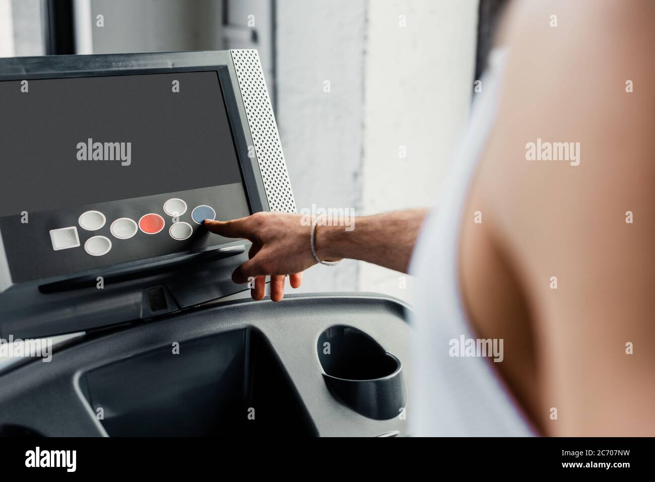 cropped view of sportsman pointing with finger at button on treadmill ...