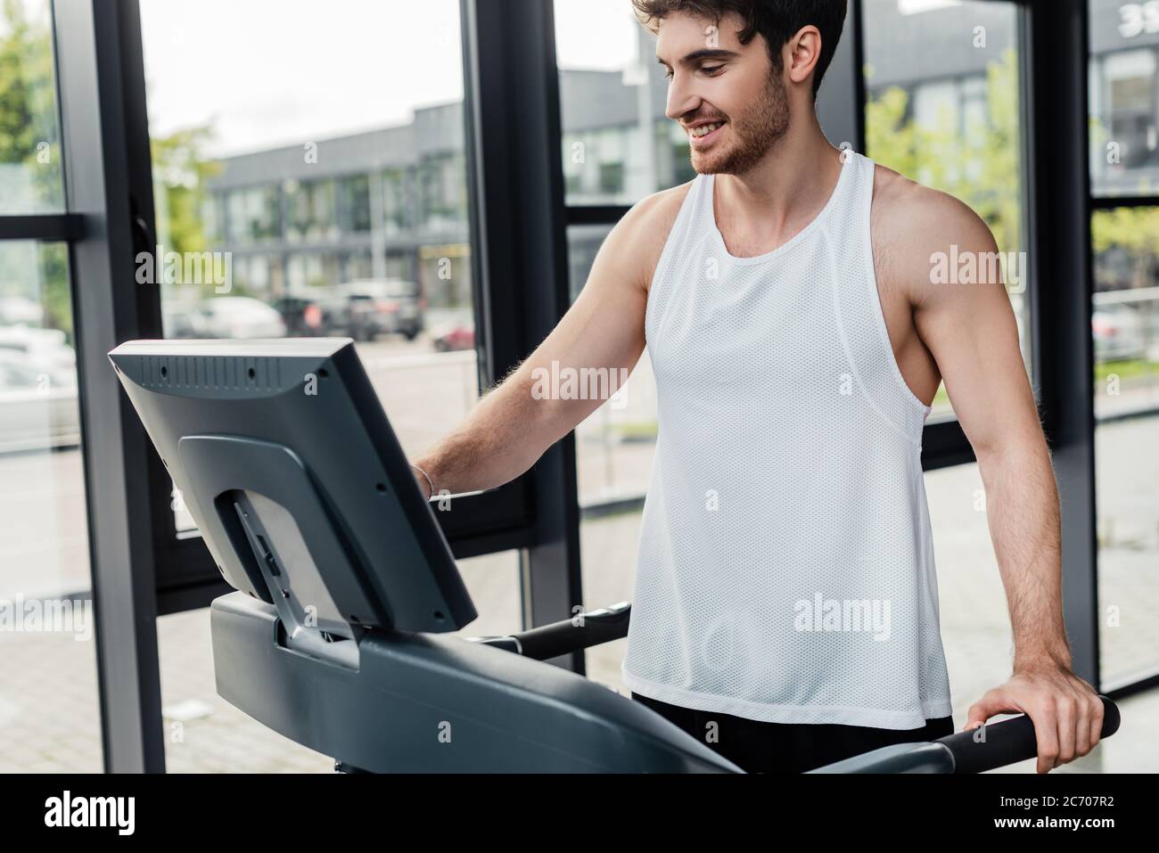 happy sportsman looking at screen on modern treadmill in gym Stock ...