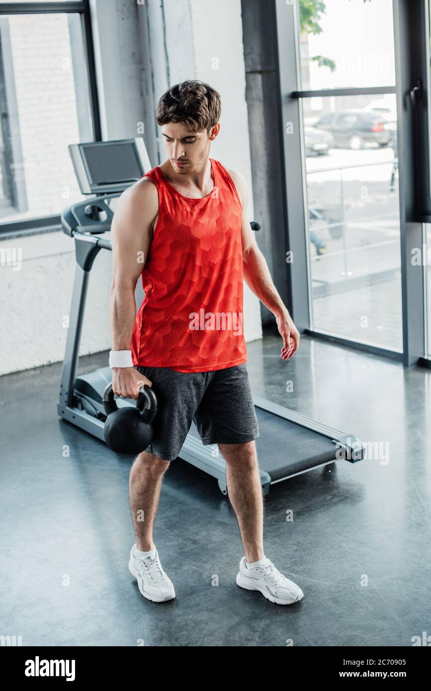 strong man holding heavy dumbbell near treadmill in sports center Stock ...